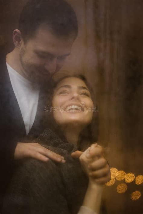 Happy Guy And His Girlfriend Dressed In Yellow Raincoats Are Walking On The Street In The Rain