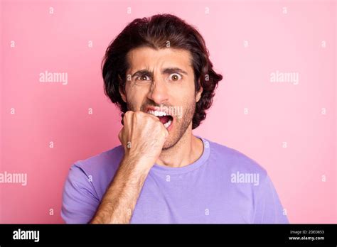 Photo Of Nervous Young Guy Bite Fist Crazy Face Wear Violet T Shirt Isolated Pastel Pink Color