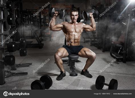 Athlete Muscular Bodybuilder In Gym Training Biceps With Dumbbel