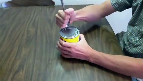 Il vous montre comment ouvrir une boite de conserve avec une cuillère