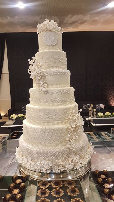 A Large White Wedding Cake Sitting On Top Of A Table Next To Cupcakes