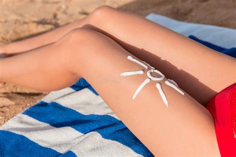Mujer Que Toma El Sol En La Playa Con Un Dibujo Del Sol En Su Pierna