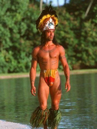 A Man Wearing A Hula Skirt Standing In The Water With His Headdress On