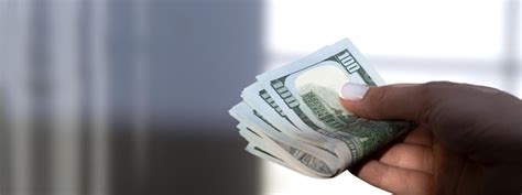 Una mano que sostiene una pila de billetes de 100 dólares Foto Premium
