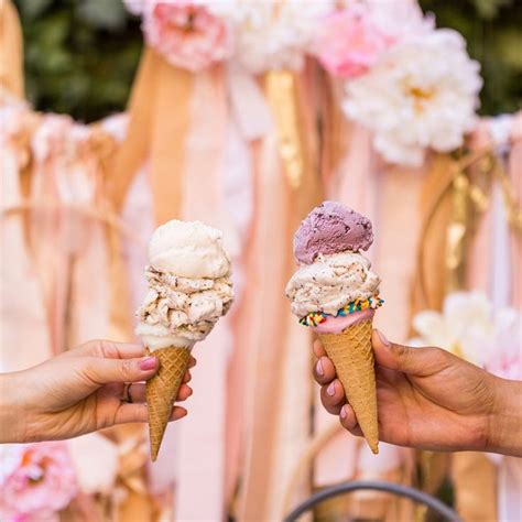 Two People Holding Ice Cream Cones In Their Hands