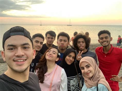 A Group Of People Standing Next To Each Other Near The Ocean
