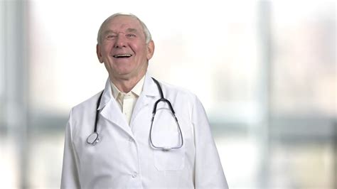 Old Doctor Laughing And Putting Hands Up Aged Friendly Physician Bright Blurred Windows In
