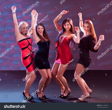 Group Of Glamorous Young Women In Evening Attire Dancing Together At A Nightclub Or Disco Stock