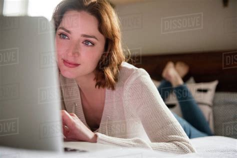 Caucasian Woman Laying On Bed Using A Laptop Stock Photo Dissolve