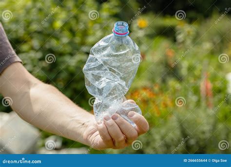 Hand Holding Crumpled Empty Plastic Bottle In The Park Stock Photo
