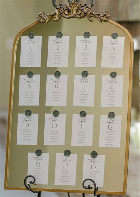 The Seating Chart Is Set Up On A Gold Framed Easel For Guests To Sign
