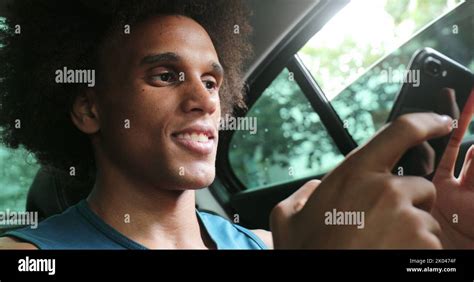 Black Man In Backseat Of Car Typing On Cellphone Smiling Riding Taxi