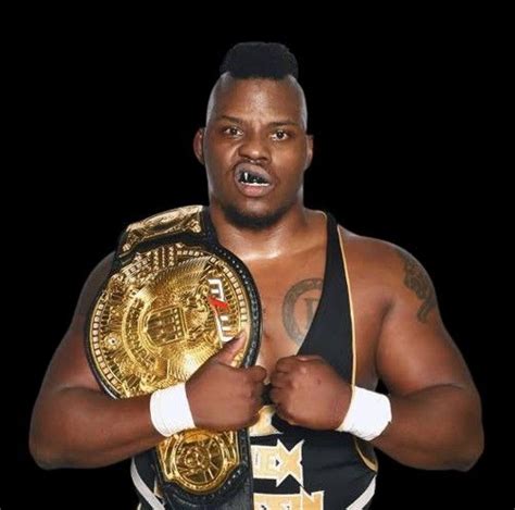 A Man Holding A Gold Wrestling Belt In His Right Hand And Looking At
