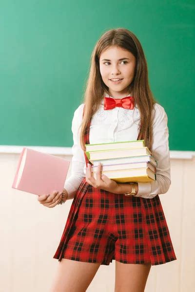 Two Pretty Schoolgirls In School Uniform Stand With Books In The