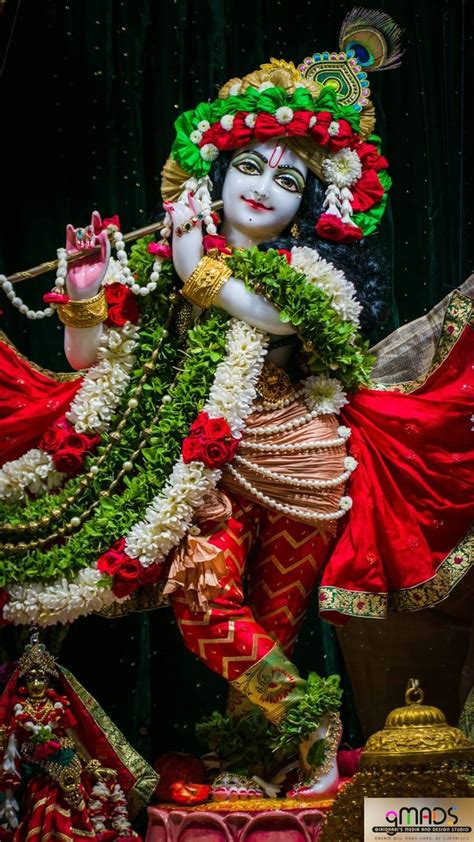 An Idol Is Displayed In Front Of A Green Curtain With Flowers On The