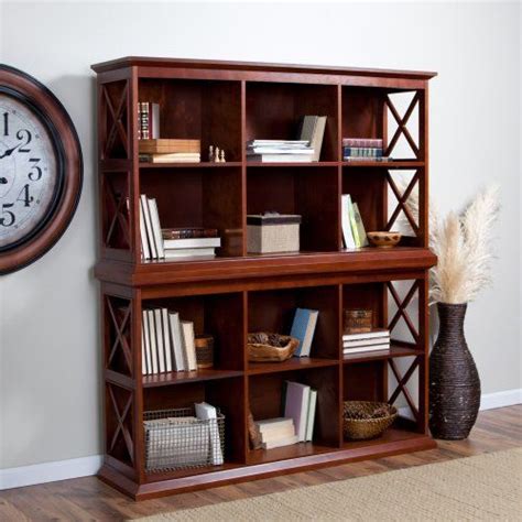 A Wooden Book Shelf With Books On It Next To A Wall Clock And A Vase
