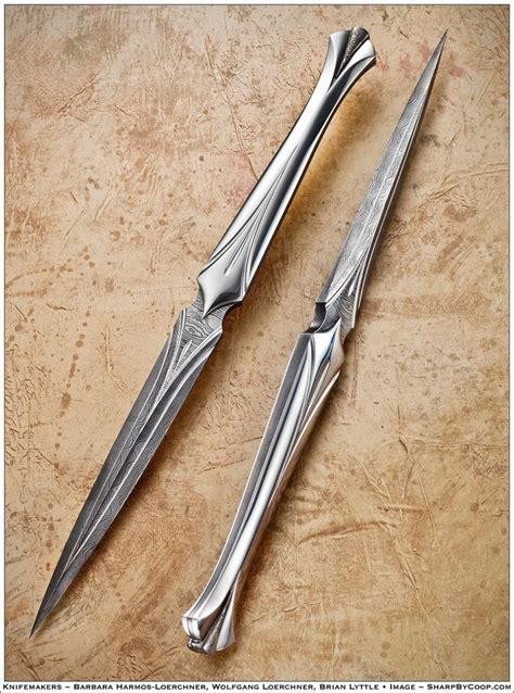 Two Silver Knives Sitting On Top Of A Wooden Table