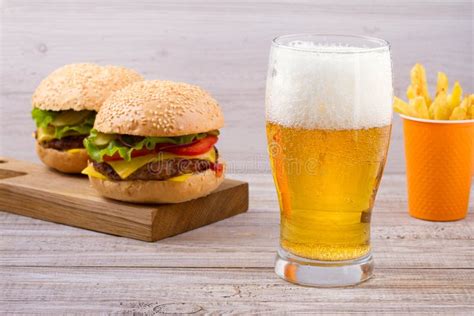 Vidrio De Cerveza Con La Hamburguesa Y Las Fritadas En Fondo De Madera