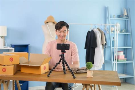 Um homem asiático está mostrando roupas na frente do smartphone