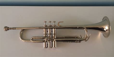 A Silver Trumpet Is Laying On A White Surface