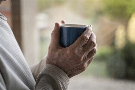 Close Up Of Man Holding Coffee Cup While Standing At Home Stock Photo
