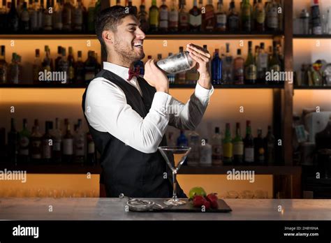 Un barman profesional fresco que hace un cóctel sacudiendo un