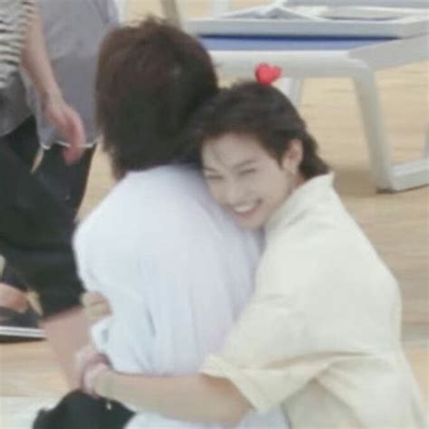 Two Women Hugging Each Other In Front Of Some People On The Beach And