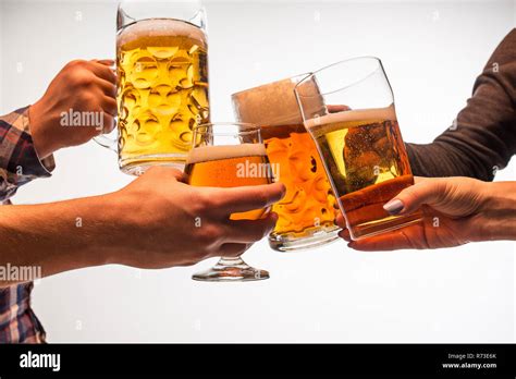 Hands With Mugs Of Beer Toasting Creating Splash Isolated On White