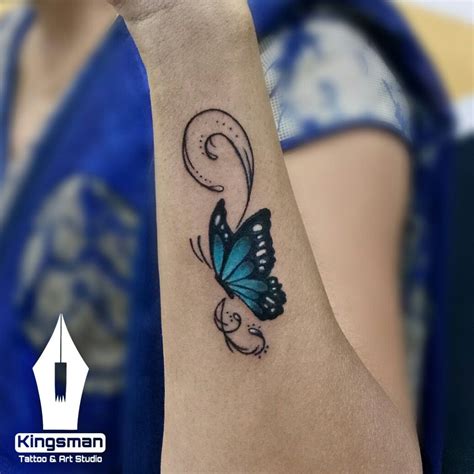A Woman S Arm With A Blue Butterfly Tattoo On The Left Side Of Her Arm