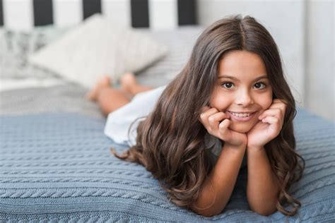 Portrait De Jolie Fille Souriante Allongée Sur Le Lit Photo Gratuite
