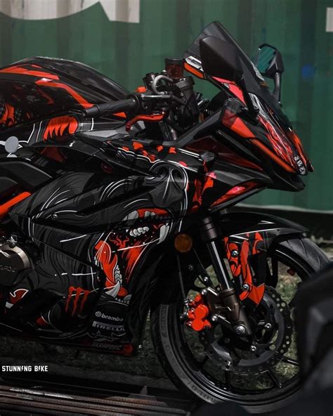 A Red And Black Motorcycle Parked In Front Of A Green Wall With