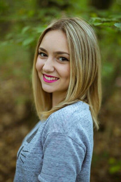 Premium Photo Vertical Shot Of A Cute Caucasian Blonde In The Woods Looking At The Camera With