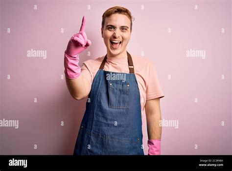 Young Handsome Redhead Cleaner Man Doing Housework Wearing Apron And Gloves Pointing Finger Up
