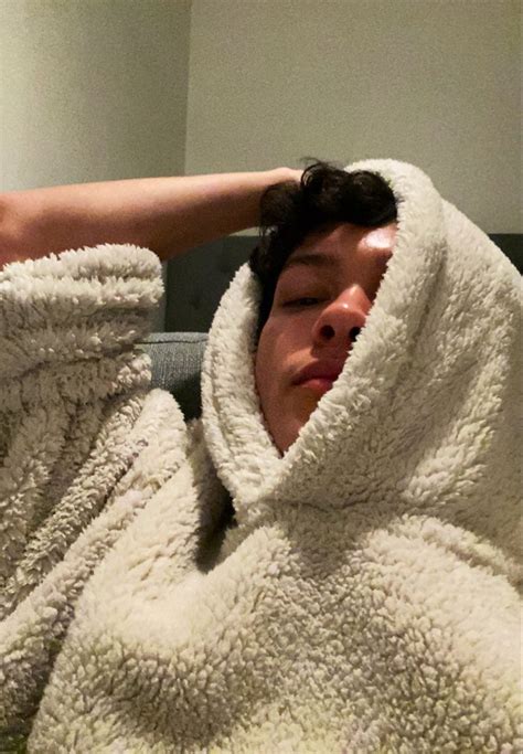 A Man In A Bathrobe Laying On A Couch With His Head Under The Covers