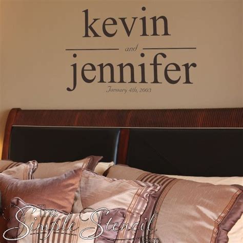 A Bedroom With A Bed Pillows And Wall Decal That Says Kevin And Jennifer