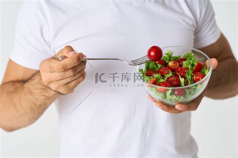 一个穿着白色T恤的男人盘子里放着沙拉和零食健康食品高清摄影大图 千库网