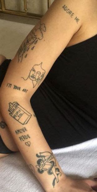 A Woman Laying On Top Of A Bed With Tattoos On Her Arm