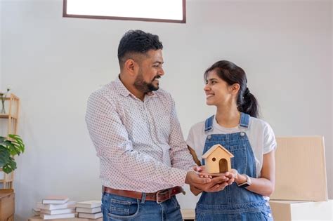 Casal feliz segurando modelo de casa no dia da mudança para casa nova