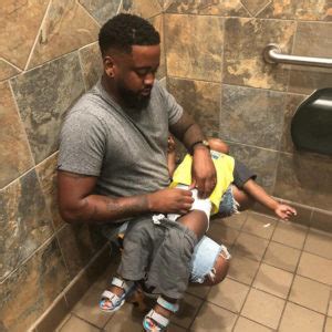La foto di un papà che cambia il pannolino del figlio nel bagno degli