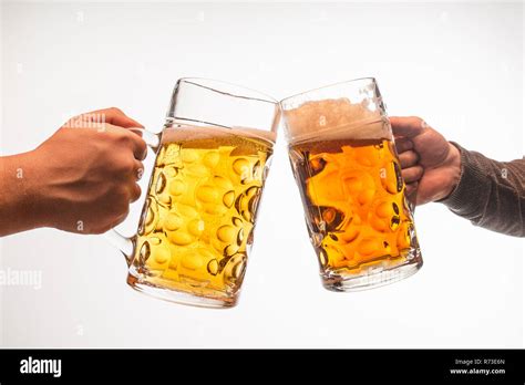 Hands With Mugs Of Beer Toasting Creating Splash Isolated On White