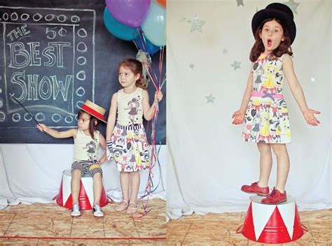 Two Girls In Dresses And Hats Standing On Top Of Stools With Balloons