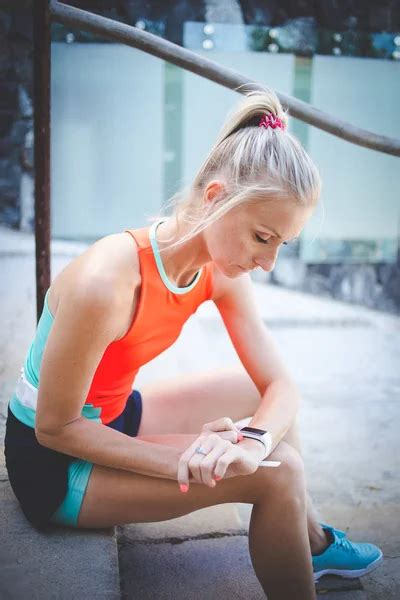 Blond Fitness Model Resting On Stairs And Checking Heart Rate On Monitor After Exercises Stock