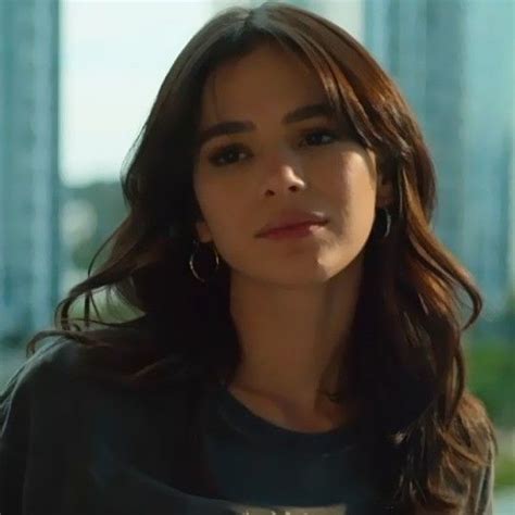 A Woman With Long Brown Hair Wearing A Black Shirt And Large Hoop