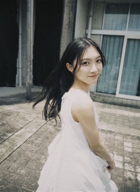 A Woman In A White Dress Is Walking Down The Street With Her Hair