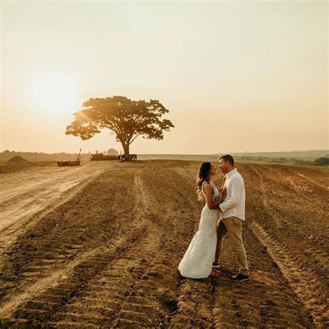 A Man And Woman Standing In The Middle Of A Dirt Road