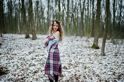 Kręcona śliczna Blondynka Z Wieńcem W Kratkę W śnieżny Las W Zimowy Dzień Darmowe Zdjęcie