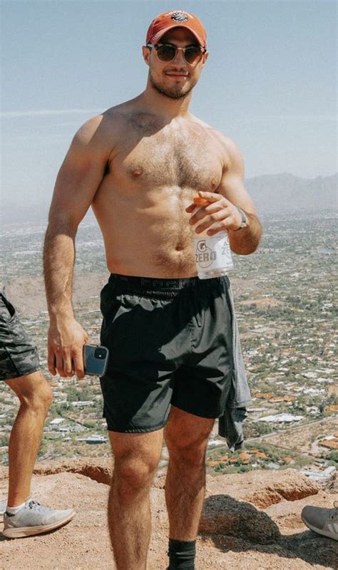 A Man Standing On Top Of A Mountain With No Shirt And Holding A Water