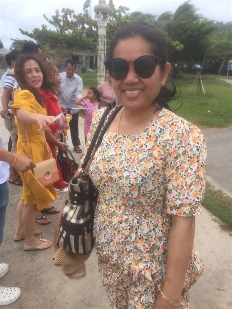 A Woman Is Standing On The Sidewalk With Her Purse In Hand And People