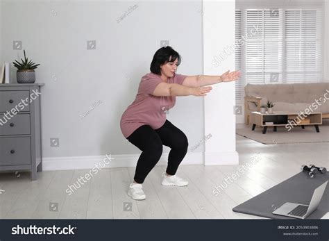 Overweight Mature Woman Squatting While Watching Stock Photo 2053903886