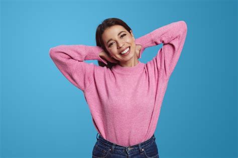 Premium Photo Young Female Model In Blue Jeans And Pink Jumper Holding Hands Behind Head And